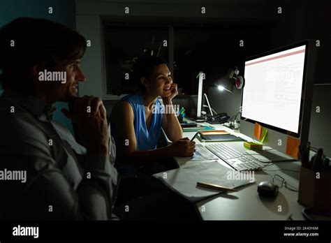 Two Diverse Male And Female Colleagues Sitting At Desk And Using Computer With Coding On Screen
