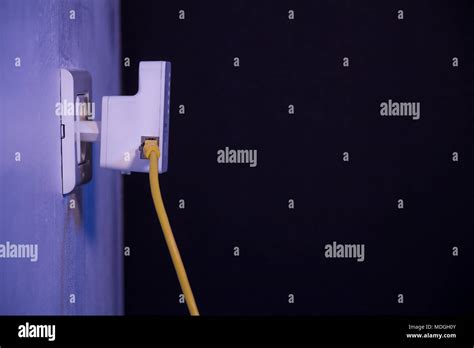 WiFi Extender In Electrical Socket On The Wall With Ethernet Cable Plugged In The Device Is In
