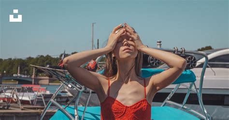 빨간색 탱크 탑과 파란색 데님 반바지를 입은 여자는 파란색과 흰색 보트에 앉아 있습니다 사진 Unsplash의 무료 여자 이미지