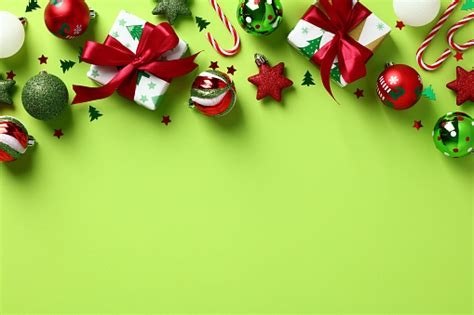 세련된 크리스마스 장식품과 선물 상자가 상단 테두리를 장식합니다 파스텔 녹색 배경에 크리스마스 장식 평면도 플랫 레이 크리스마스