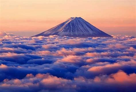 A Mountain In The Distance Surrounded By Clouds At Sunset Or Dawn With