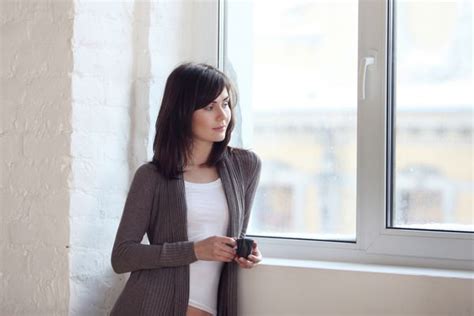 دختر جوان زیبا کنار پنجره است و از پنجره به بیرون نگاه می کند 1489047