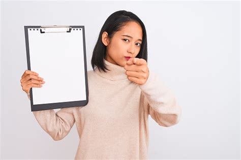 카메라와 당신에 게 손가락으로 가리키는 고립 된 흰색 배경 위에 서 클립 보드를 들고 젊은 중국 검사 여자 손 기호 앞에서 긍정적이 고 자신감 제스처 가리키기에 대한 스톡