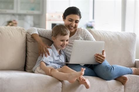 Happy Indian Mother With Caucasian Son Using Laptop Having Fun Stock