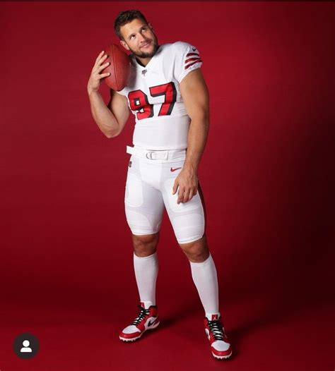A Man Holding A Football In His Right Hand And Posing For A Photo On A