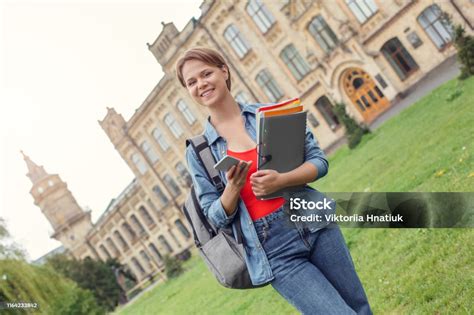 대학 캠퍼스에서 배낭을 가진 젊은 학생은 노트북을 들고 스마트 폰을 찾고 카메라를 기쁘게 대학교에 대한 스톡 사진 및 기타 이미지 대학교 학생 교육 Istock