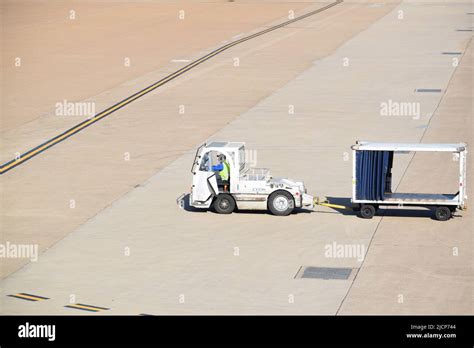 A United Airlines Ramp Service Worker Driving A Tractor And Pulling An