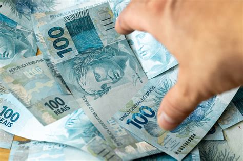 Foto De Dinheiro Do Brasil Mão Alcançando O Maço De Cédulas Centenas De Reais Conceito