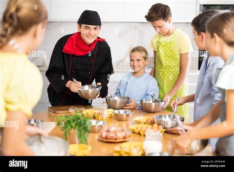 Young Chef Giving Culinary Classes To Group Of Interested Tweens Stock