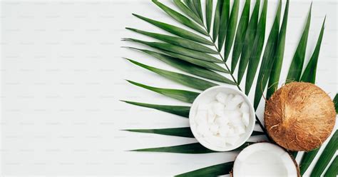 반쪽과 코코넛 플레이크가 그릇에 뿌려진 코코넛 과일 흰색 바탕에 열대 야자 잎 플랫 레이 평면도 여름 배경입니다 사진 Unsplash의 건강한 라이프스타일 이미지