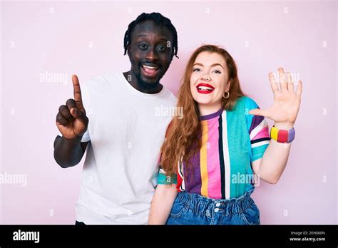 Interracial Couple Wearing Casual Clothes Showing And Pointing Up With Fingers Number Six While