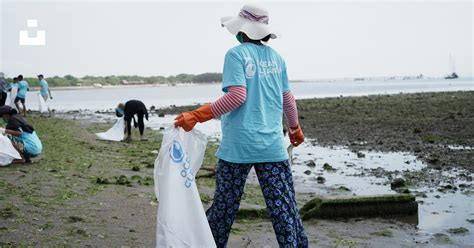 낮 동안 해변에서 검은 짧은 코트 개를 들고 하얀 태양 모자를 쓴 여자 사진 Unsplash의 무료 바다 이미지