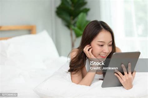 아름다움 아시아 여자 미소와 집에서 그녀의 침대에 컴퓨터 태블릿을 사용 하 여 소셜 미디어와 멀티미디어를 사용 하 여 태블릿에 휴가 휴식 20 24세에 대한 스톡 사진 및