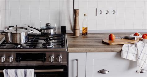 강철 오븐 냄비 야채 후추 향신료 나무 테이블 위에 기름을 곁들인 나무 도마에 칼이 있는 현대적인 주방에서 음식을 요리합니다 가정 음식 그레이 색상의 세련된