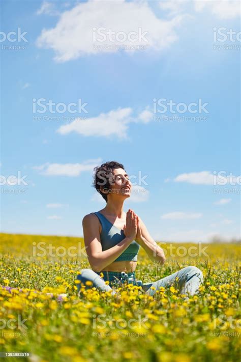 화창한 날에 화려한 야생화와 푸른 하늘로 가득한 초원에서 요가를 명상하고 연습하는 젊은 여성 자연에서의 영혼 탐구와 영적 휴식 젠 스타일에 대한 스톡 사진 및 기타 이미지