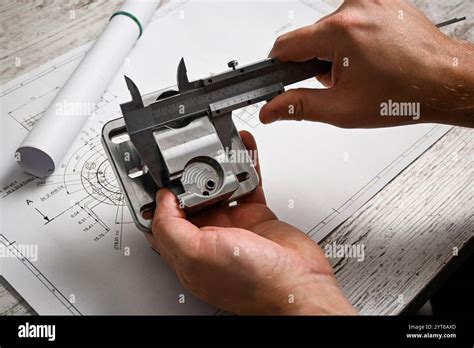 Engineer Using Caliper To Measure A Machined Part Comparing It With Its