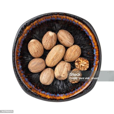 검은 접시 컷 아웃에 전체 및 절반 육두구 씨앗 흰색 배경에 고립 된 접시에 유기농 무스카트 씨앗 향신료와 조미료 개념을위한 Myristica Fragrans의 건조한 과일