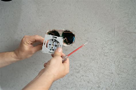 전기 기술자는 스크류 드라이버를 사용하여 소켓을 벽의 전선에 연결합니다 Diy에 대한 스톡 사진 및 기타 이미지 Diy