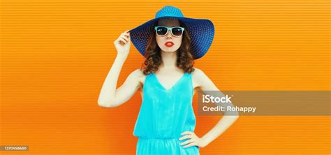 여름 밀짚 모자를 쓰고 포즈를 취하는 아름다운 젊은 여성 모델의 초상화 오렌지 색 배경에 파란색 드레스 여자에 대한 스톡 사진 및 기타 이미지 Istock