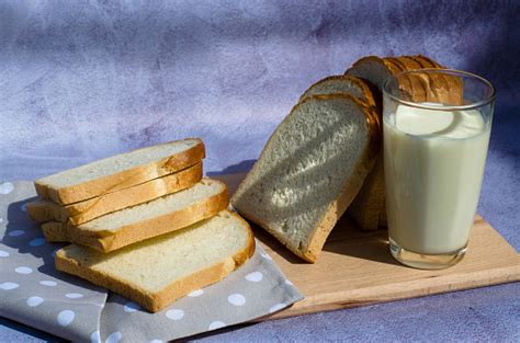 흰 빵과 딱딱한 그림자가 있는 커다란 우유 한 잔을 슬라이스합니다 흰색 물방울 무늬가 있는 회색 소재의 나무 접시에 빵과 우유 0명에 대한 스톡 사진 및 기타 이미지