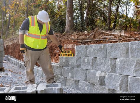 On New Property Where Retaining Block Wall Is Being Built Construction Worker Is Erecting Block