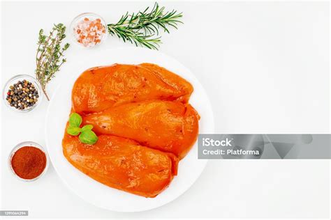 흰색 바탕에 흰색 접시에 빨간 소스에 생 절인 치킨 필레와 요리를위한 향신료가 있습니다 공간을 복사합니다 식이 닭고기 원료 제품 구운 신선한 절인 닭고기 다이어트 고기 0