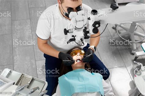 검은 마스크와 장갑에 조 수와 함께 남자 치과 환자를 현미경을 사용 하 여 처리 합니다 새로운 기술의 사용을 가진 현대 치과 치과 의사에 대한 스톡 사진 및 기타 이미지