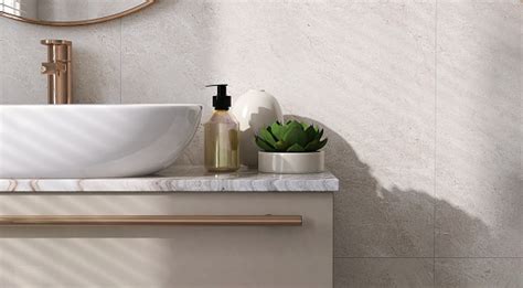 대리석 카운터 탑이있는 베이지 색 욕실 화장대와 창문에서 햇빛을 받아 관엽 식물의 꽃병이있는 흰색 둥근 세라믹 세면대의 현대적이고 최소한의 디자인 0명에 대한 스톡 사진 및