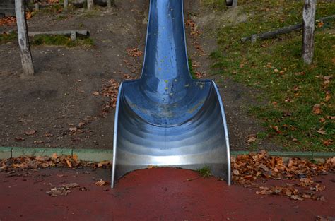 잔디 언덕과 나무 팔리세이드가있는 필드에 스테인레스 스틸 슬라이드 타탄 고무 패드에 영향을 미치는 어린이를 슬라이딩하기위한 대형 광택 튜브 튜브의 끝은 열린 쓰루입니다 0