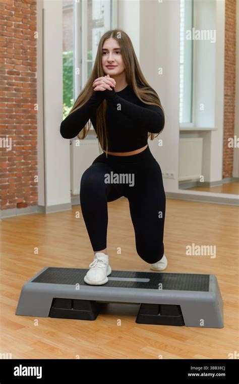 Young Woman In Black Sportswear Performing A Step Lunge On An Aerobic