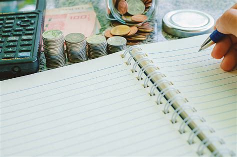 지폐 동전 유리 항아리와 비즈니스 금융 및 투자 개념 계획 계산기의 스택와 빈 노트북에 작성 하는 펜을 들고 손 경제에 대한 스톡 사진 및 기타 이미지 Istock