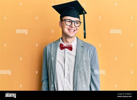 Young Caucasian Nerd Man Wearing Glasses And Graduation Cap Looking To