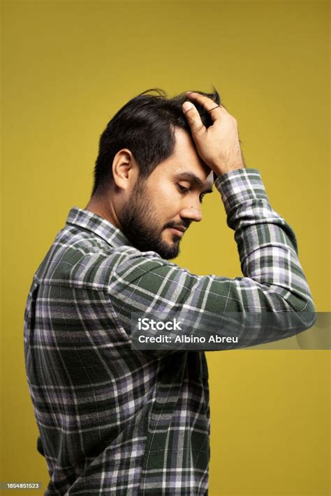 Man In Profile Running His Hand Through His Hair And Looking Down Stock