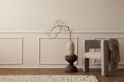 복사 공간 현대적인 안락 의자 베이지 색 격자 무늬 가지가있는 꽃병 나무 커피 테이블 꼰 깔개 및 개인 액세서리가있는 우아한 거실 인테리어의 미니멀리스트 구성 가정 장식 템