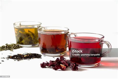 검은 색 빨간색 녹차와 세 개의 유리 컵은 흰색 배경에 마른 차 잎과 꽃이 있습니다 레드 핫 히비스커스 차 녹차 홍차 뜨거운