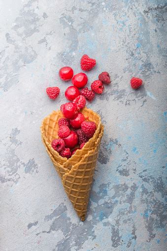 와플 아이스 크림 콘 신선한 여름 체리와 라즈베리로 가득 한 와플 콘의 창조적 인 컨셉 사진 와플 콘에서 열매가 떨어집니다