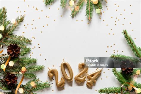 크리스마스 트리 가지와 금색 촛불 번호 2024 황금 장식 리본 원뿔 및 별이 있는 크리스마스 카드 배너 밝은 배경입니다 모형 새해 복 많이 받으세요 12월에 대한 스톡