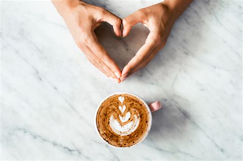 신선한 카푸치노와 여자 손의 핑크 컵 흰색 대리석 테이블 배경에 하트 모양 거품에 클래식 라떼 아트와 초콜릿 텍스트를 위한 빈 장소 복사 공간 커피 중독 갈색에 대한 스톡