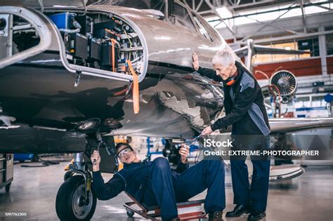 노인 여성 항공기 정비사 비행기의 착륙 기어 철회 시스템에 노력 하는 그녀의 동료에 게 도움을 대출 비행기 수리공에 대한 스톡 사진 및 기타 이미지 Istock