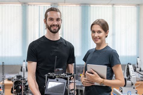 Portrait Of Male And Female Engineers Researchers Testing And Controlling AI Robot At Academy