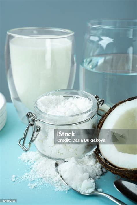 코코넛 제품 고기가 반으로 자른 오픈 코코넛 유리 항아리에 코코넛 파우더 푸른 배경에 우유를 심는 다 등등 투영 공간을 복사합니다 개념 대체 우유 식물성 가루로 빻은에 대한