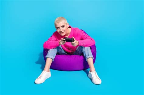 Joyful Young Woman In A Trendy Pink Sweater Sitting On A Purple Bean