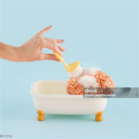 브러시와 젊은 여성의 손은 고립 된 파스텔 블루 배경에 거품 욕조에서 인간의 뇌의 모델을 세싱합니다 정신 건강 뇌 안개 건강 치료 또는 세뇌의 최소한의 추상적 인 개념 사람