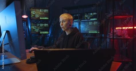 Female Caucasian Hacker Working On Computer In Front Of Big Screen And
