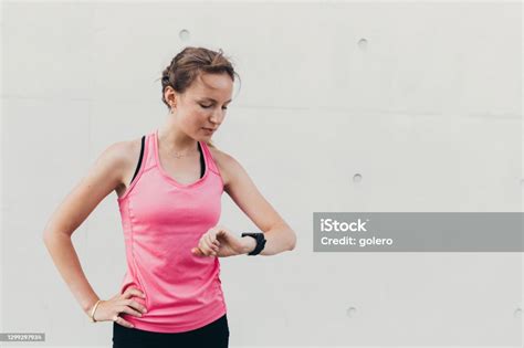 콘크리트 벽 앞에서 스마트 시계를 확인하는 젊은 스포츠 우먼 스마트시계에 대한 스톡 사진 및 기타 이미지 스마트시계 보기 정적 활동 여자 Istock