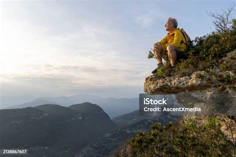 성숙한 등산객이 절벽 가장자리에 앉아 밖을 내다보고 있습니다 60 64세에 대한 스톡 사진 및 기타 이미지 60 64세 가장자리 개성 개념 Istock