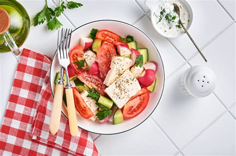 무 오이 토마토 후추 페타 치즈와 향신료 후추 올리브 오일을 회색 슬레이트 돌 또는 콘크리트 배경에 흰 그릇에 넣습니다 건강한 식품 개념 맨 위 보기입니다 가벼운에 대한