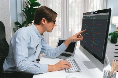 it developer pointing on coding software on pc comparing laptop