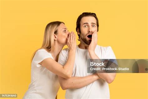 흰색 티셔츠에 놀란 감정적 인 남자의 귀에 속삭이는 재미있는 밀레니엄 백인 여성 T 셔츠에 대한 스톡 사진 및 기타 이미지 T 셔츠 스튜디오 촬영 커플 Istock