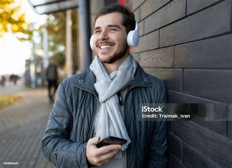 성인 쾌활한 남자는 휴대 전화에서 흰색 오버 이어 헤드폰으로 음악을 듣고 미소로 먼 곳을 바라 봅니다 35 39세에 대한 스톡 사진 및 기타 이미지 Istock